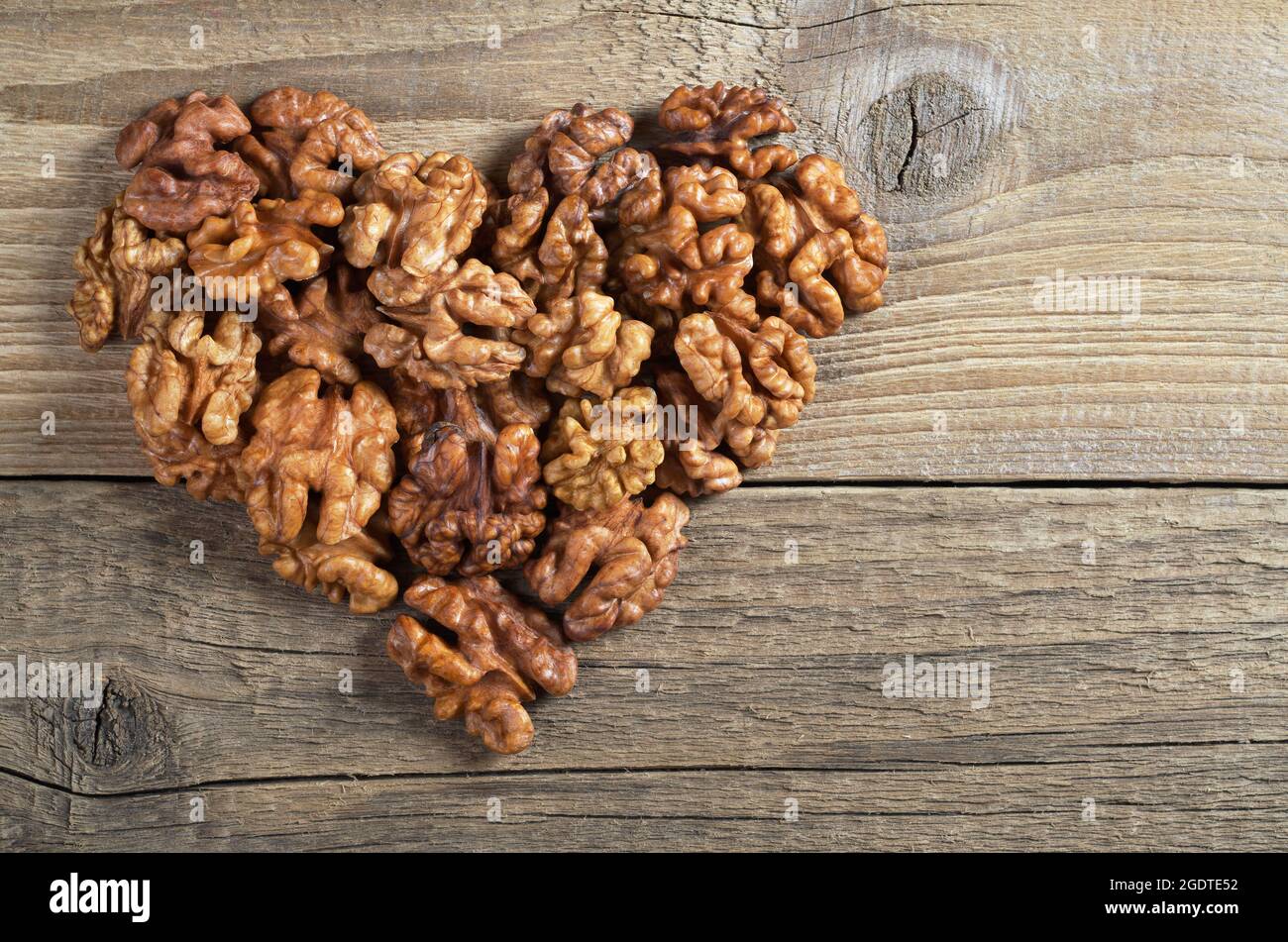 Walnut kernels in shape of heart on old wooden background, top view ...