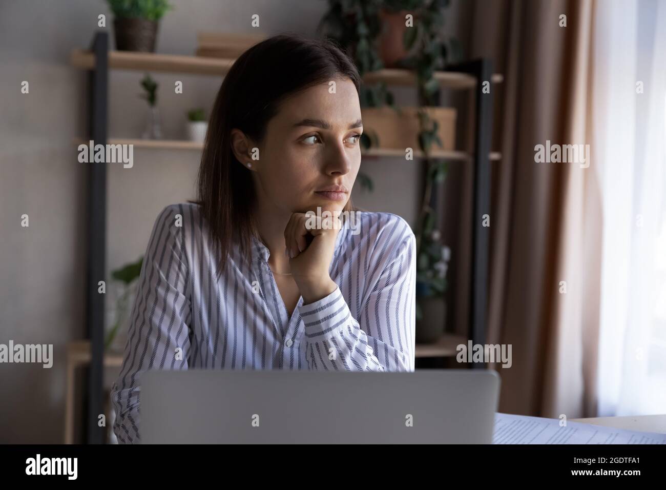 Serious young woman distracted from computer job thinking Stock Photo ...
