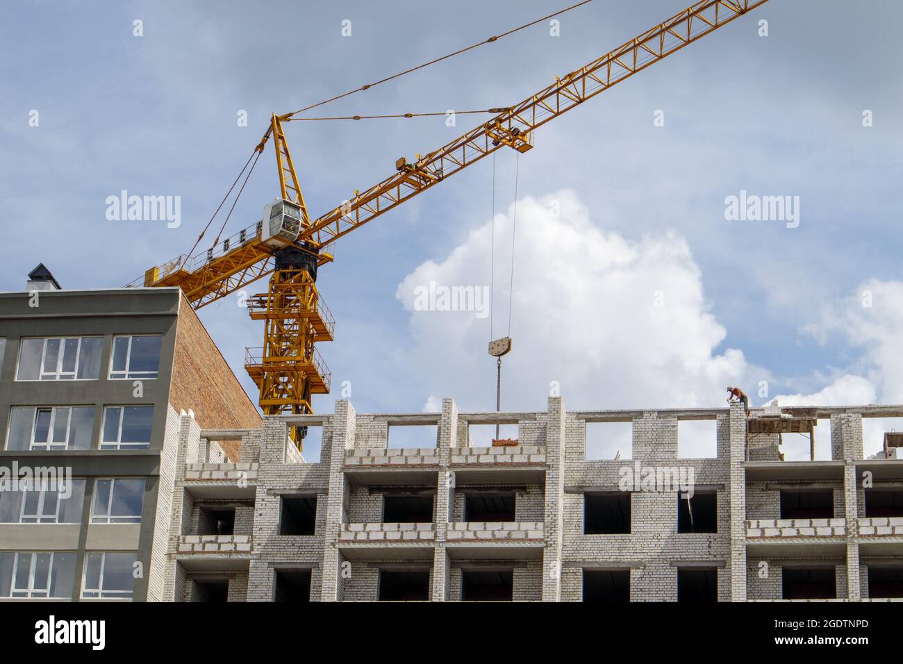 Construction crane on an unfinished residential building against the ...