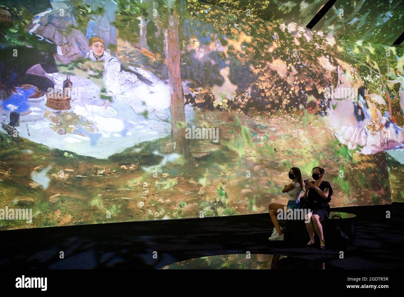 Two women attend the Beyond Monet exhibit, observing the animated art ...