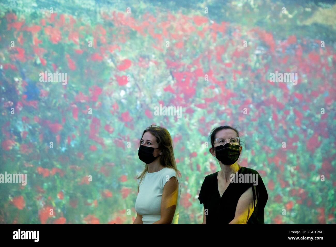 Two women attend the Beyond Monet exhibit, observing the animated art ...