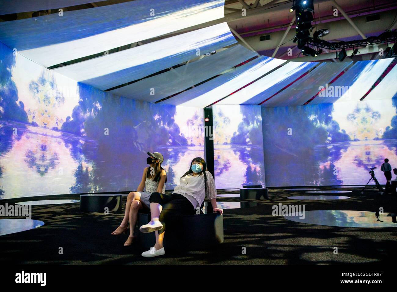 Two women attend the Beyond Monet exhibit, observing the animated art ...