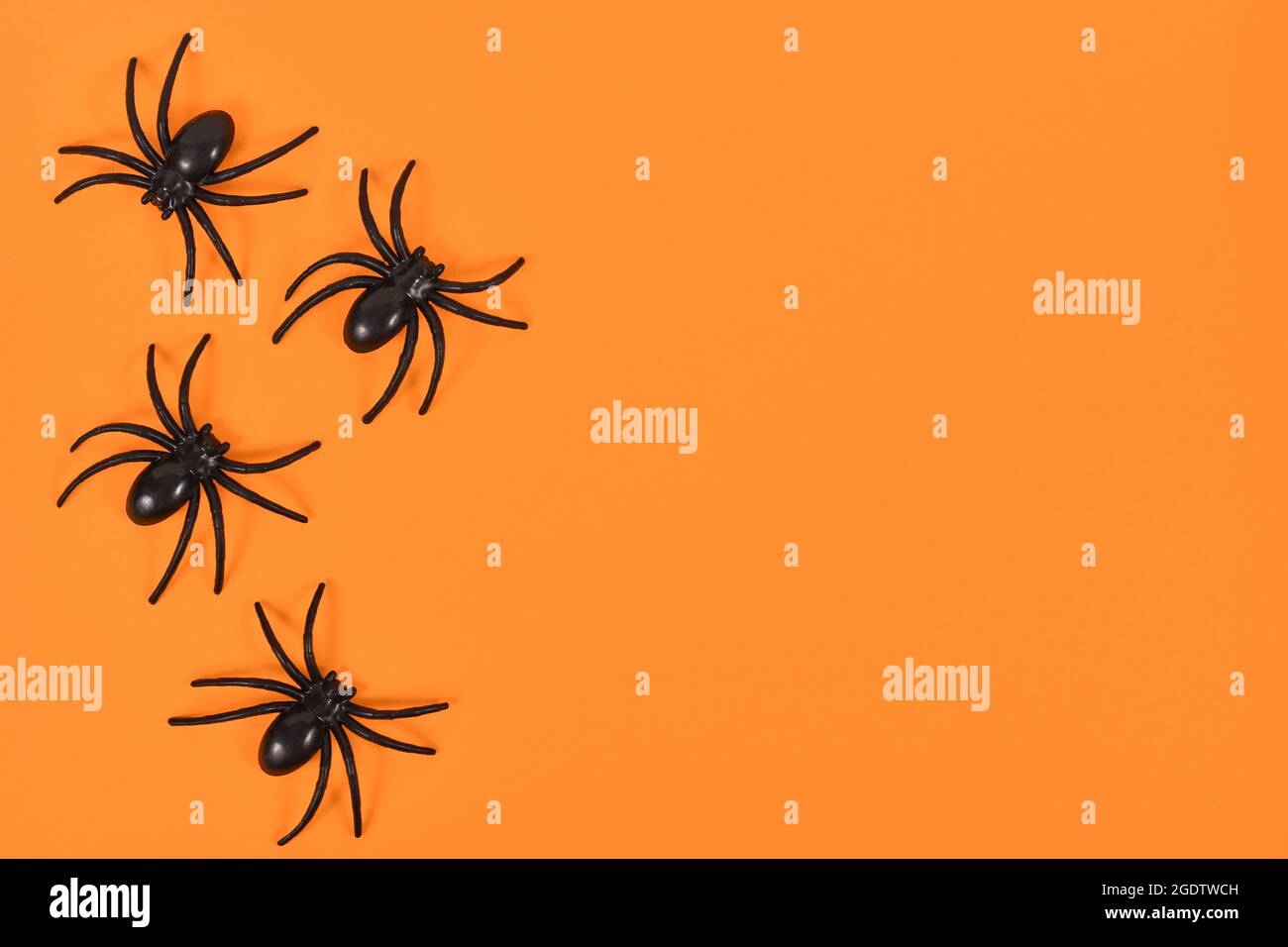 Plastic spiders on side of bright orange Halloween background with ...