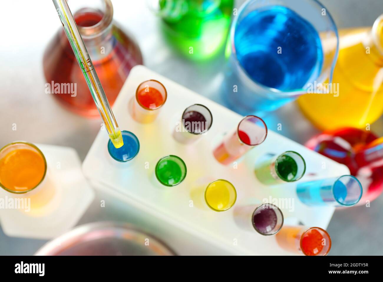 Different laboratory glassware with colorful liquid on color background ...