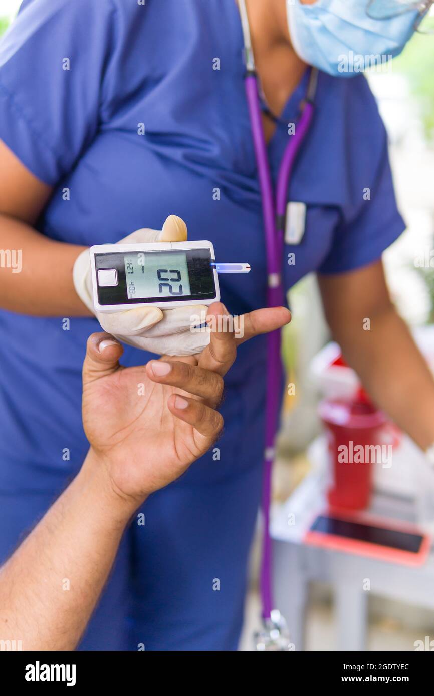 A doctor measuring patients blood glucose with a glucometer in a ...