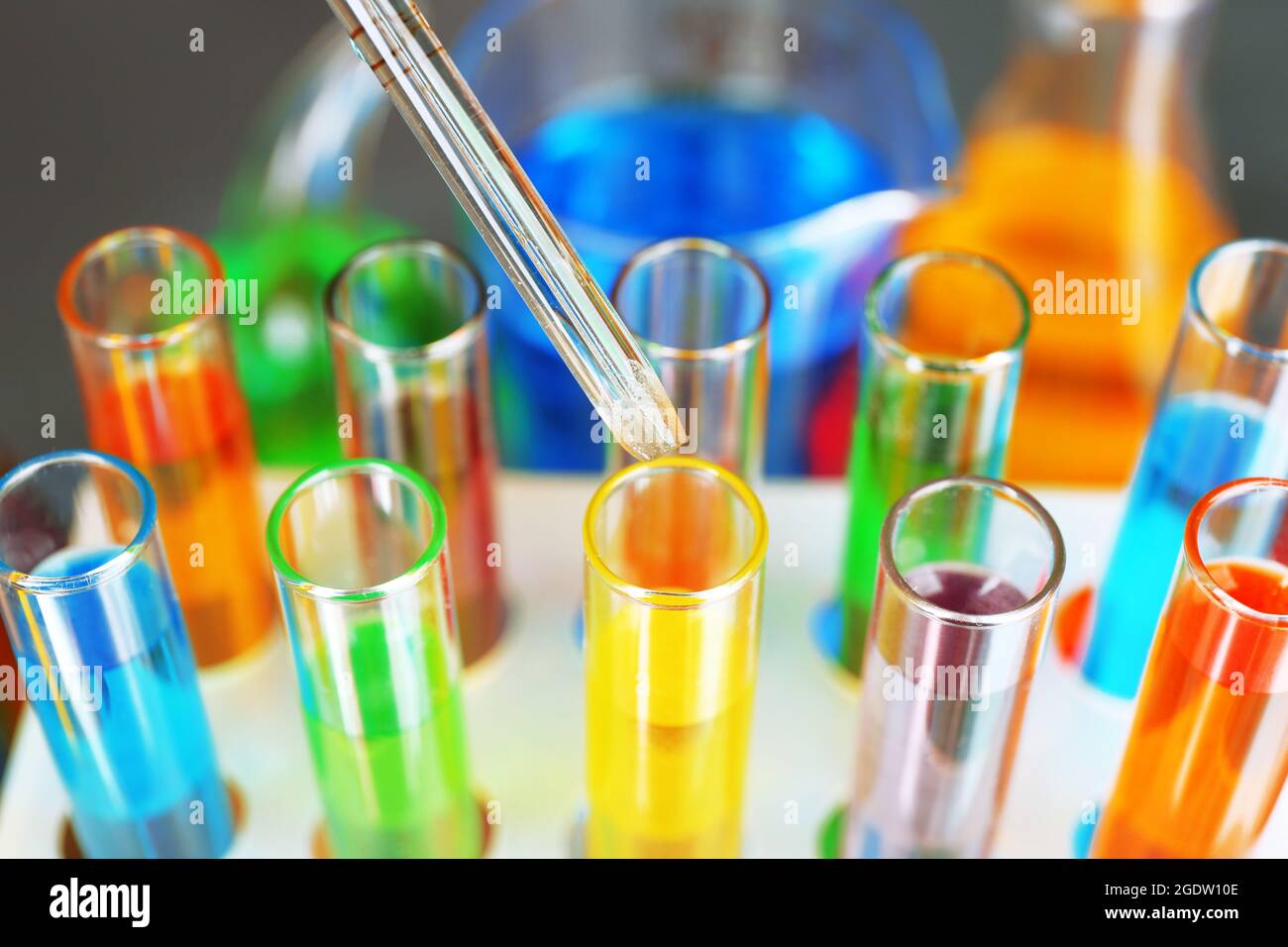 Different laboratory glassware with colorful liquid on color background ...