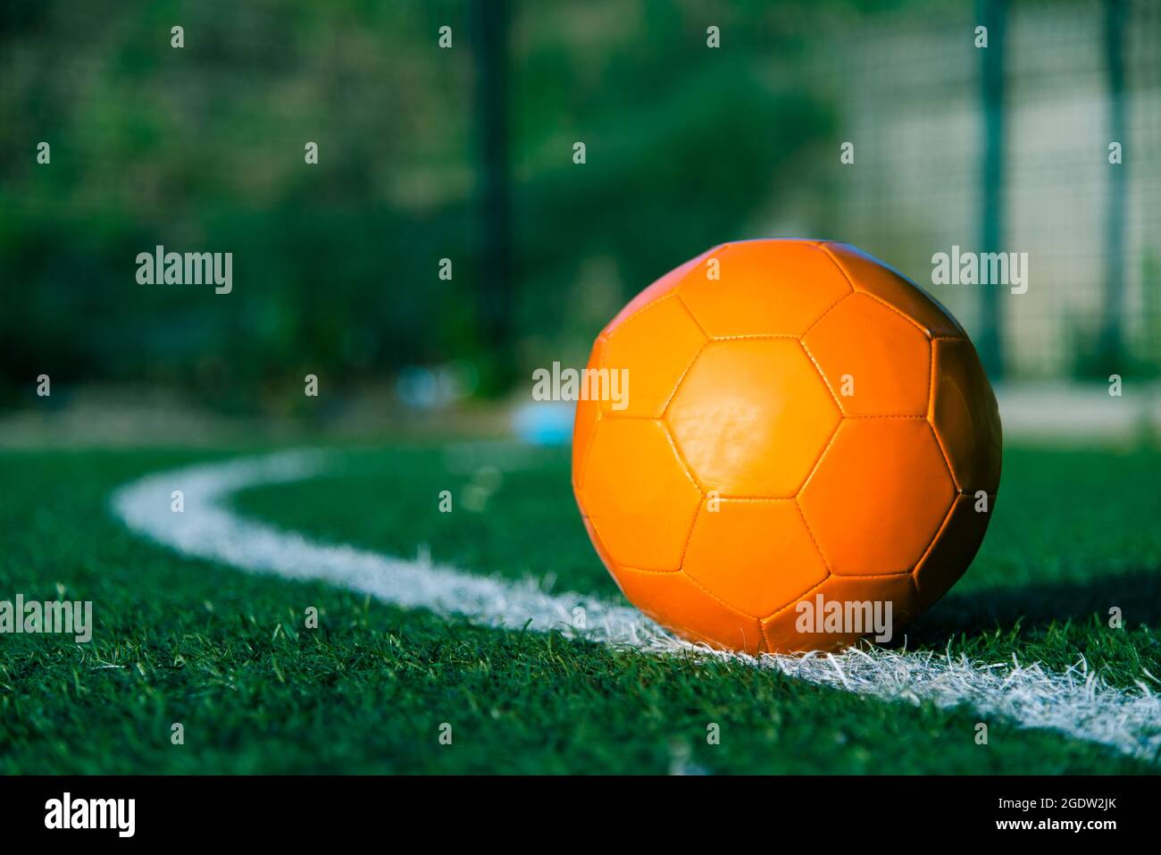 Orange soccer ball on the field of play Stock Photo - Alamy
