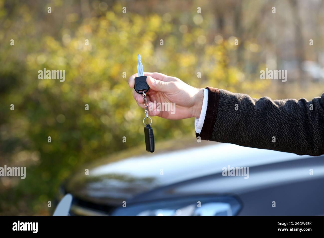 Male hand with car key on car background Stock Photo - Alamy