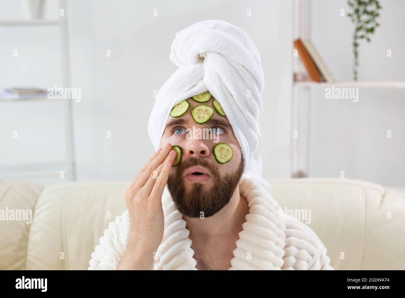 Bearded funny man enjoys with a cosmetic mask on his face made from ...
