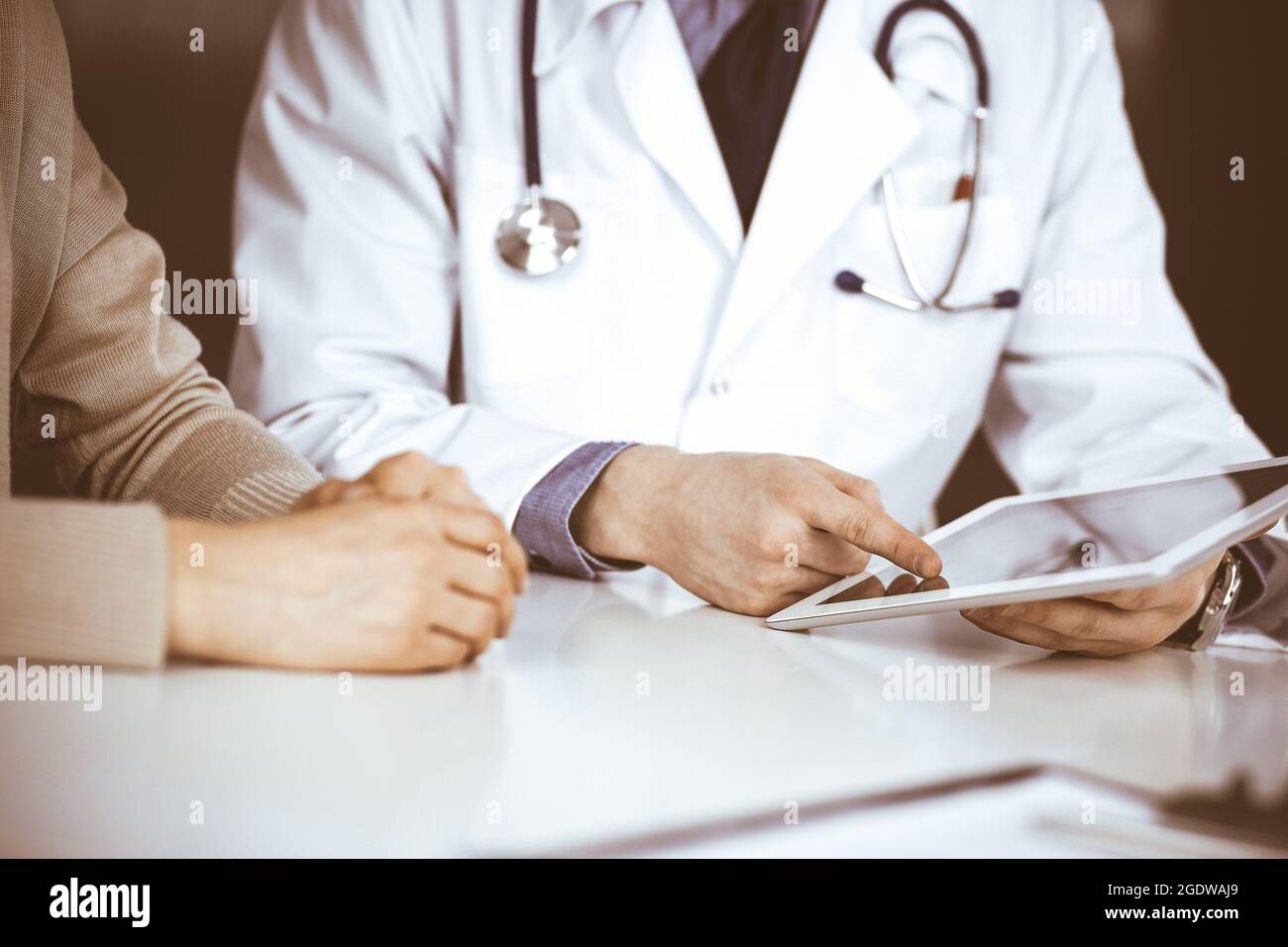 Unknown male doctor and patient woman discussing something while ...