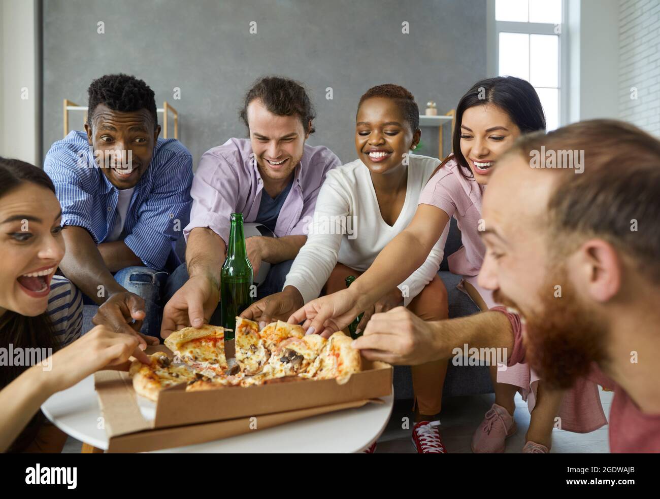 Group of happy young diverse friends taking pieces of delicious pizza ...