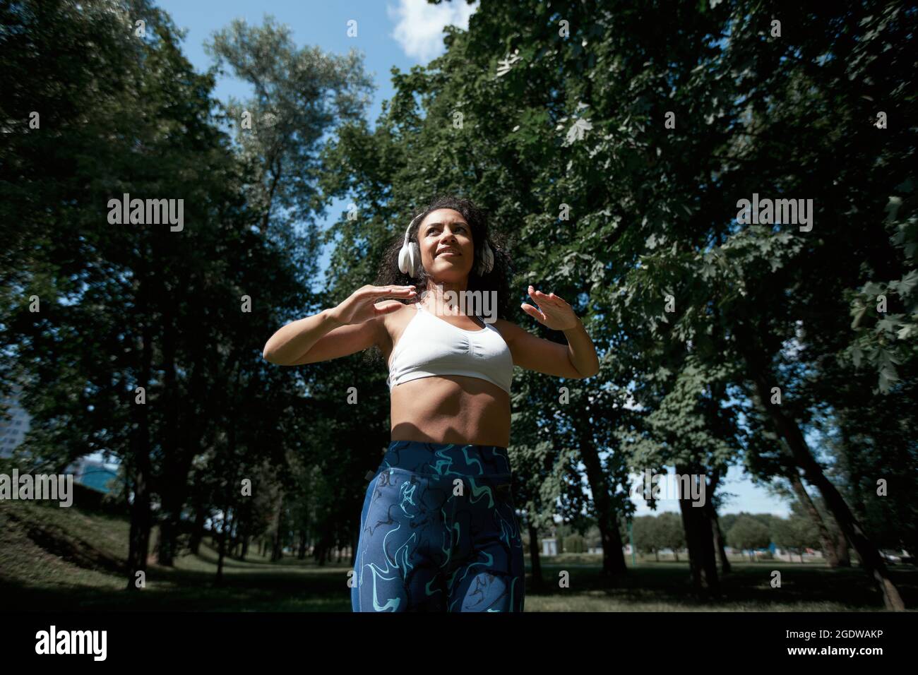 smiling woman with headphones performing fitness exercises in a Stock ...