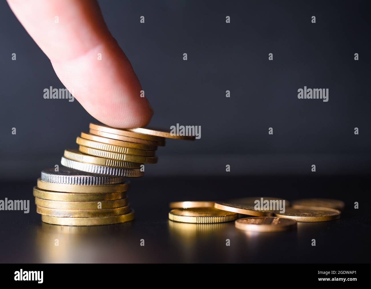 Hand destroys a tower of coins on a black background Stock Photo - Alamy