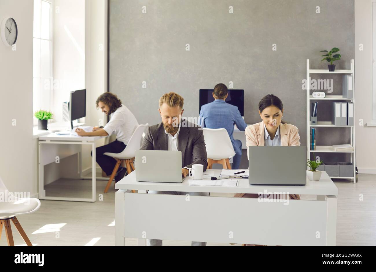 Team of employees sitting at office desks and working on laptop and ...