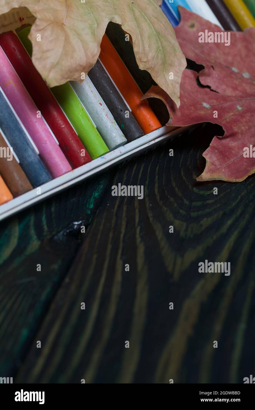 A set of pastels crayons for school. They lie in a box on pine boards ...