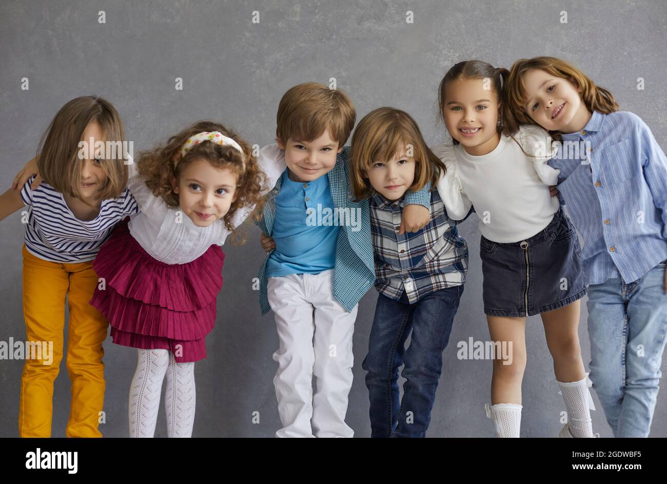 Group portrait of happy little children standing in studio, huddling ...