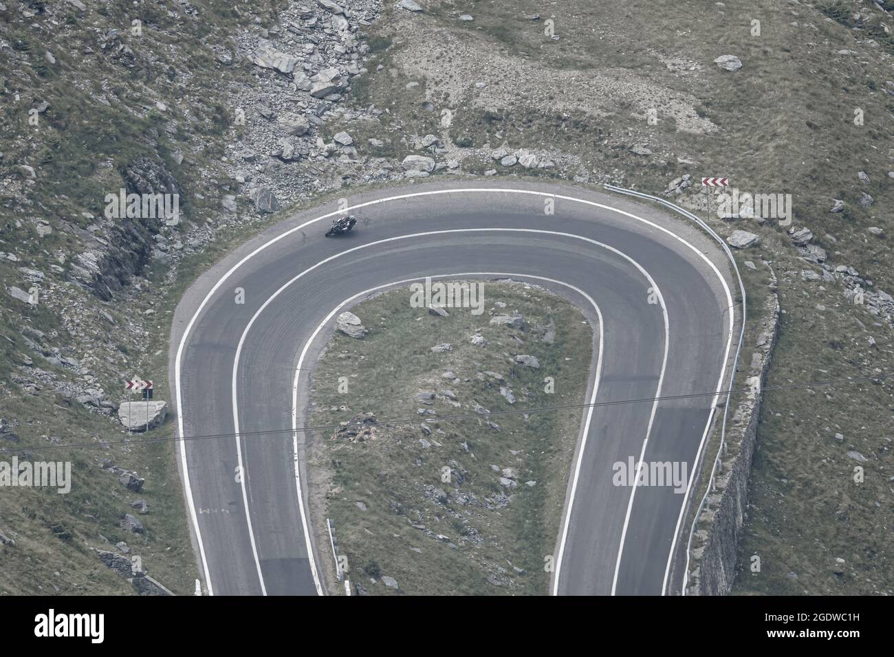 Motorcycle riding on twisted road in the mountains aerial view ...