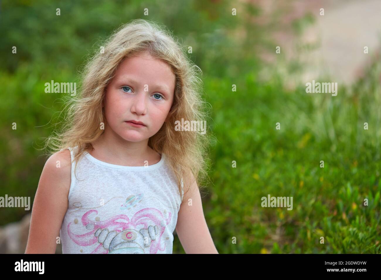 portrait of baby girl on background of greenery. Girl posing against ...