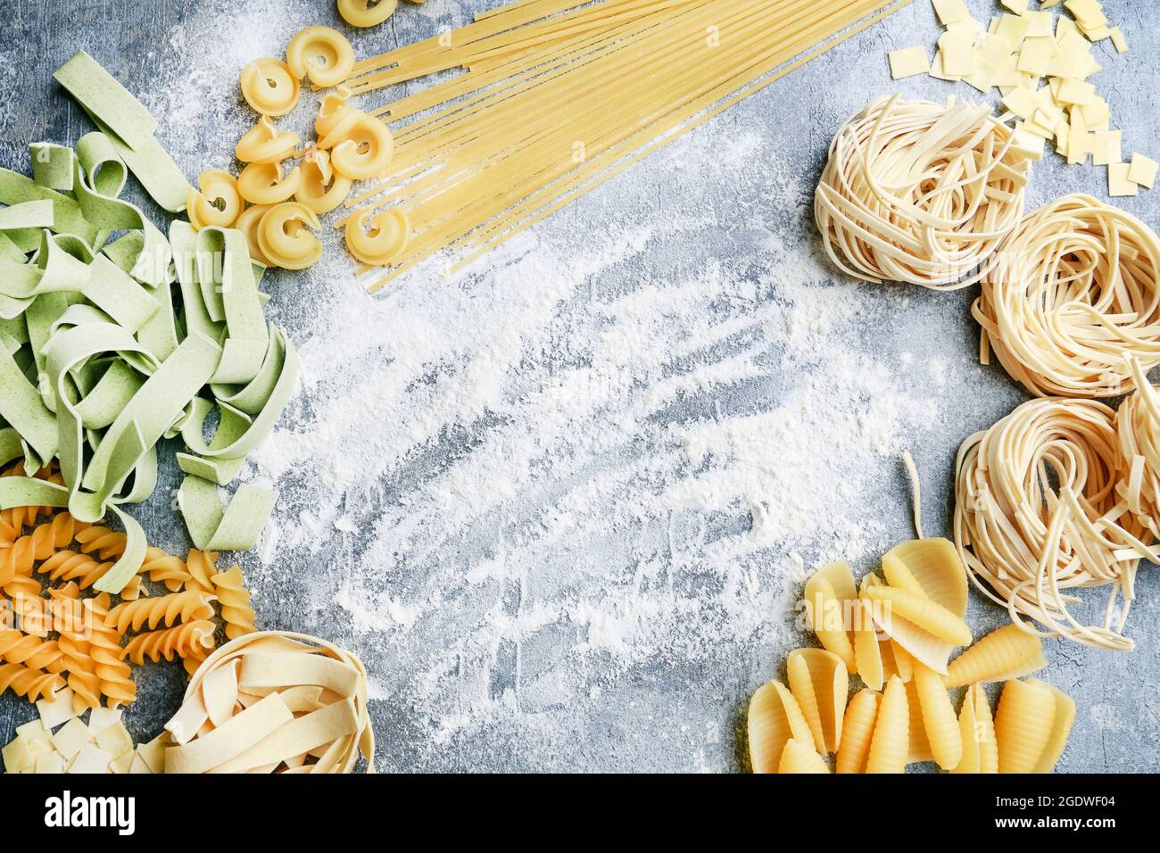 Mixed types and shapes of italian pasta on grey stone background. Copy ...