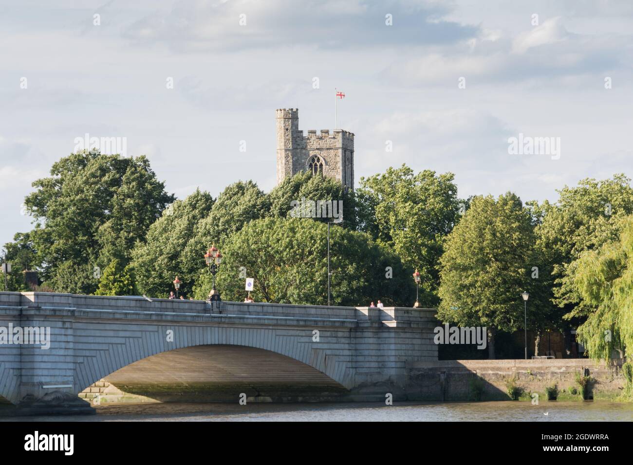 People walking across Putney Bridge with All Saints' Church Fulham in ...