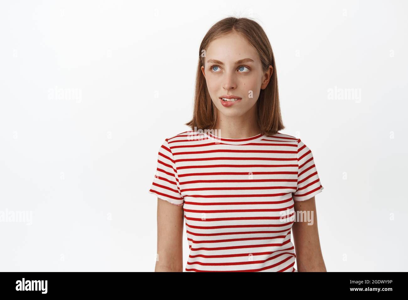 Image of thoughtful blond girl wants something, biting lip and looking ...