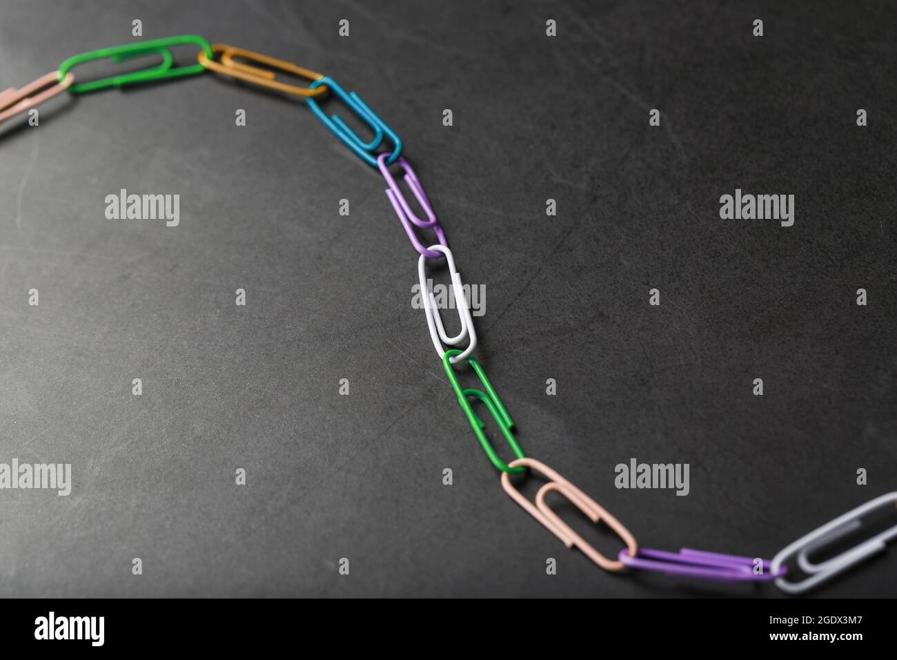 Multi-colored paper clips with a chain on a black background. Business ...