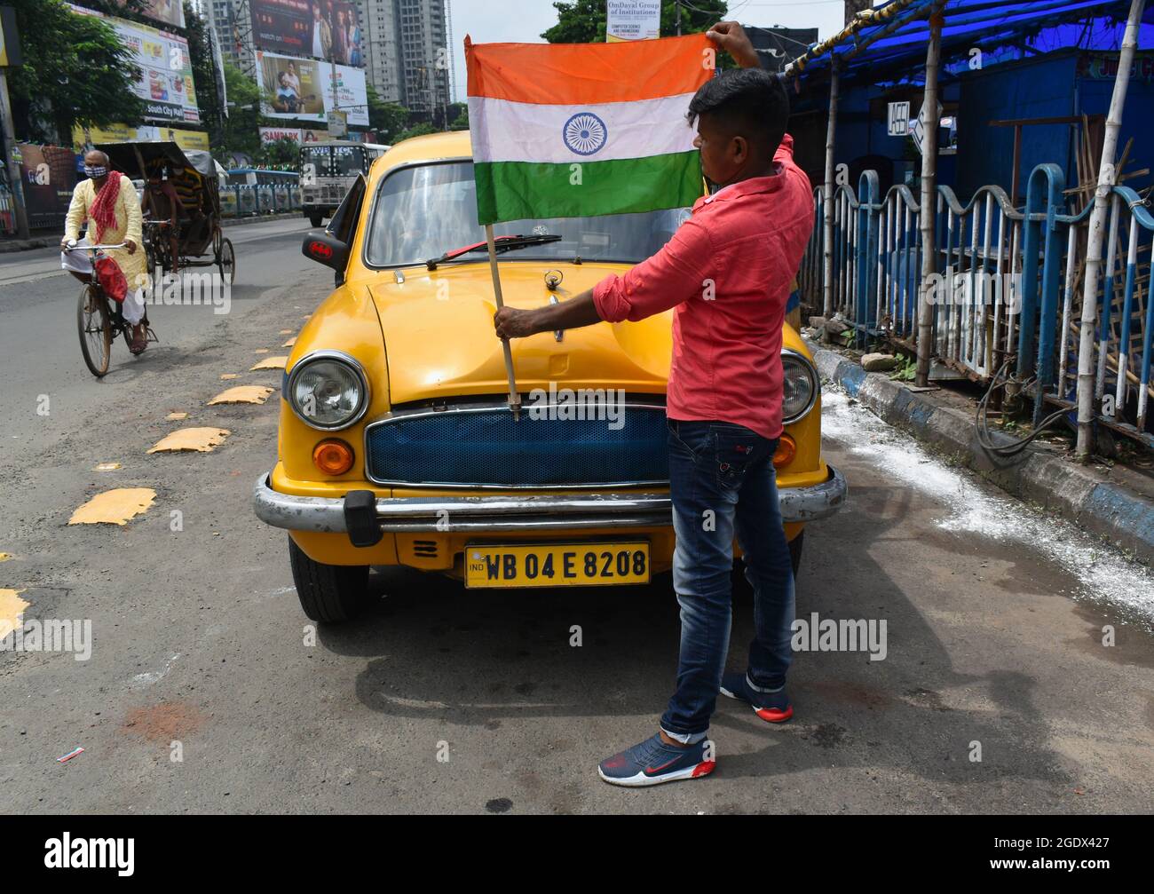 Kolkata, India. 15th Aug, 2021. A taxi driver installing a National ...