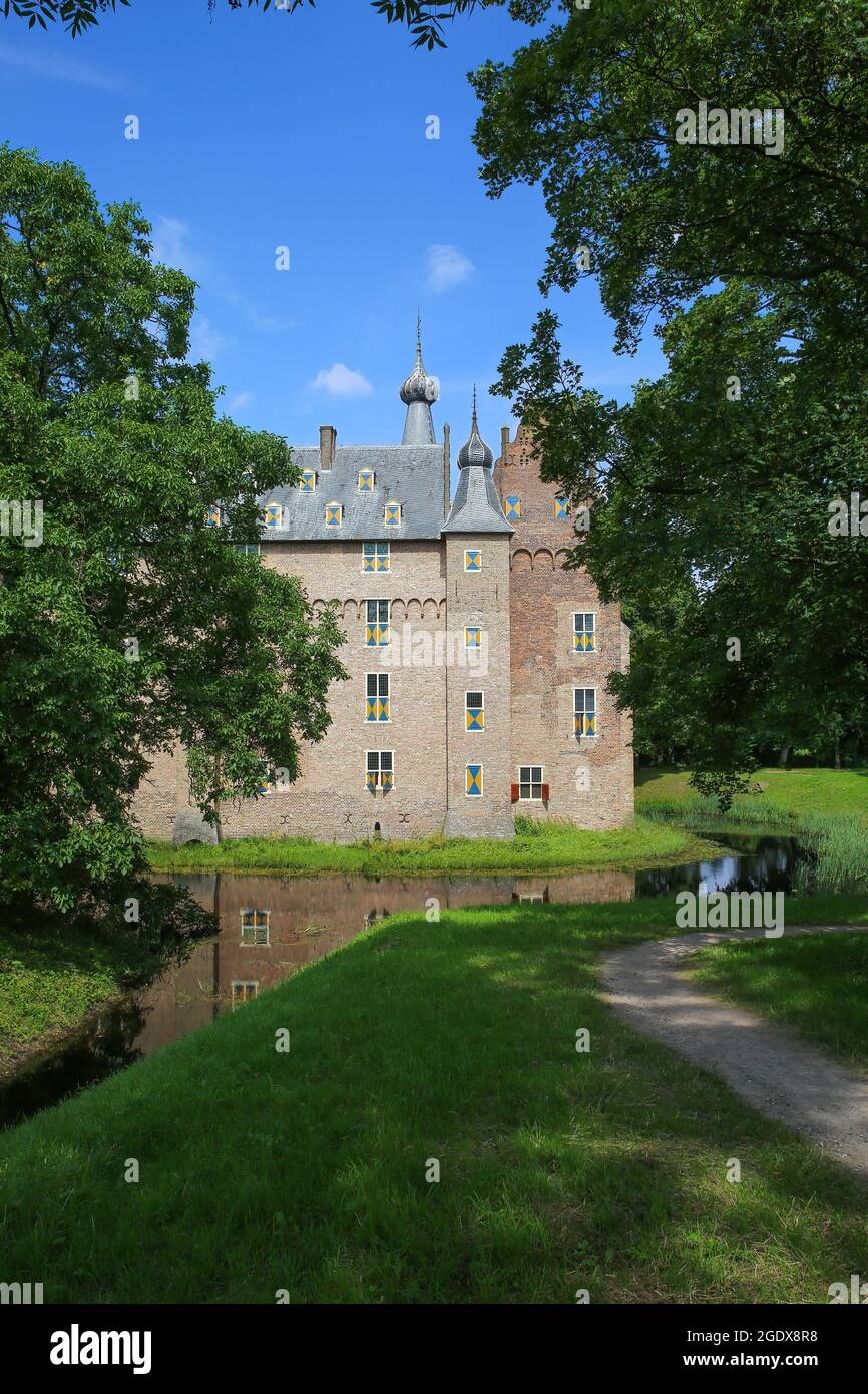 View beyond green trees on dutch water castle from 14th century against ...