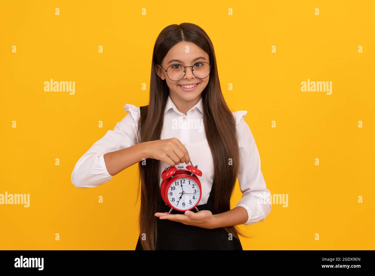 happy nerd child with alarm clock. school kid in uniform and glasses ...