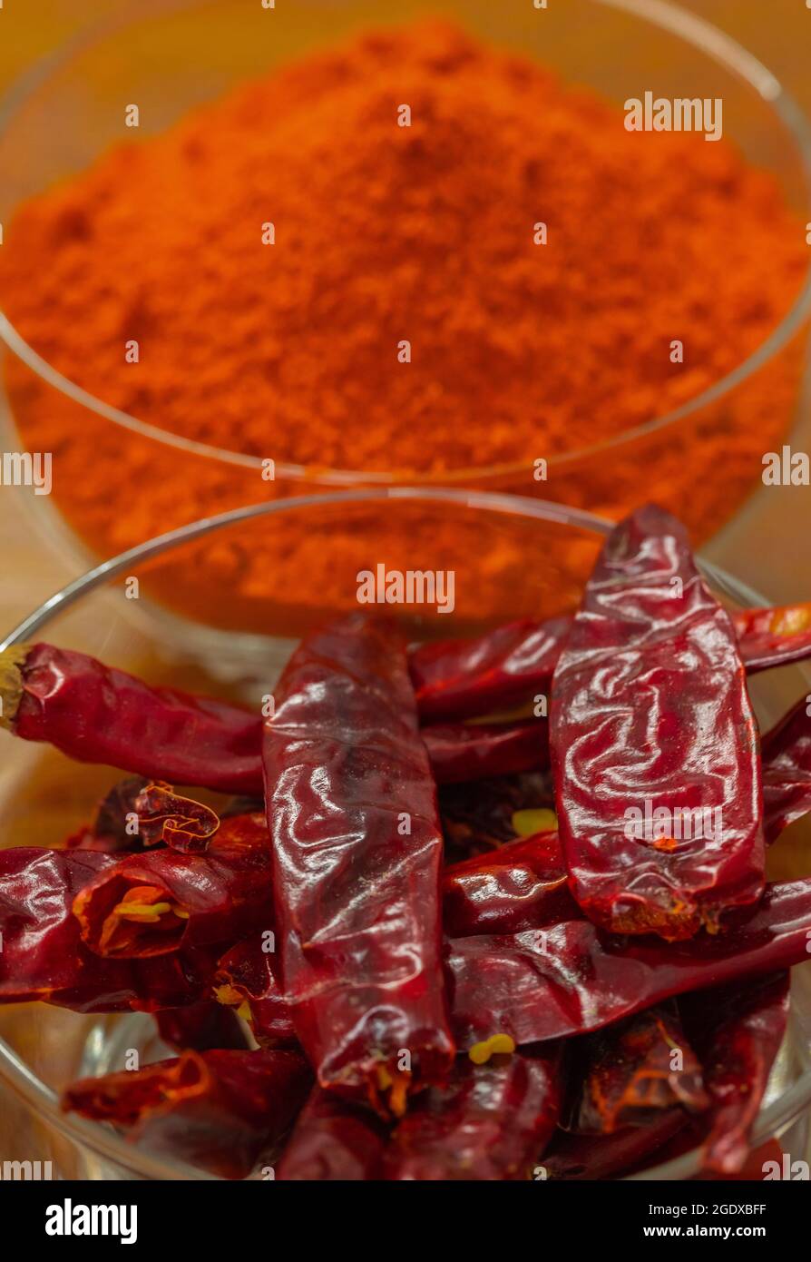 Top view of dry red chillies and red chilli powder bowls kept side by ...