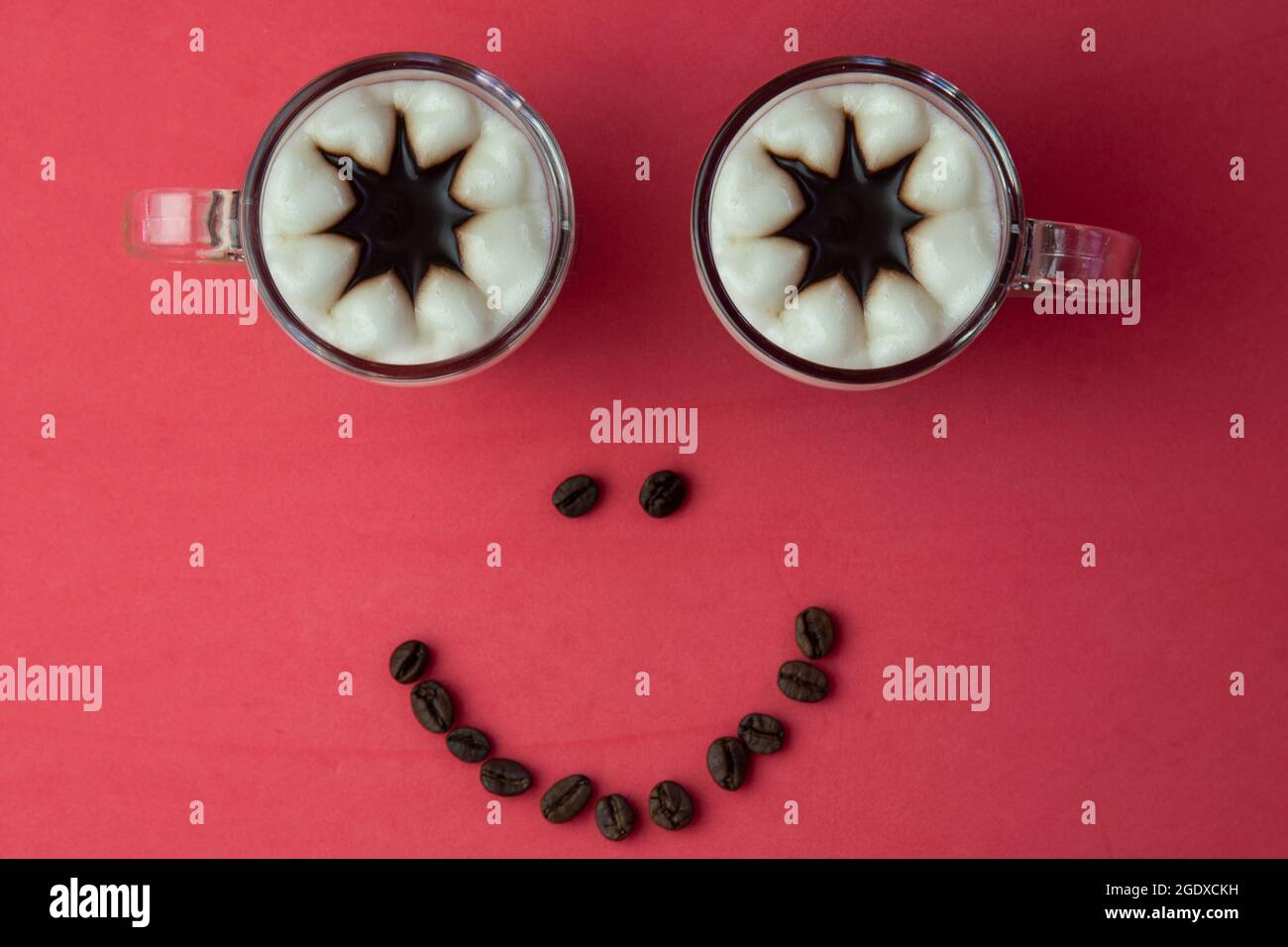 funny face made of cups of coffee and coffee beans on a red background ...