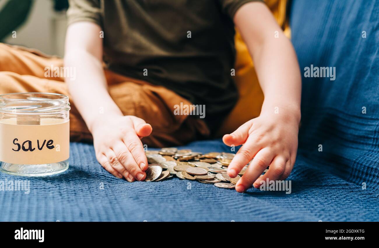 Close up of Little child kid boy hands grabbing and putting stack coins ...
