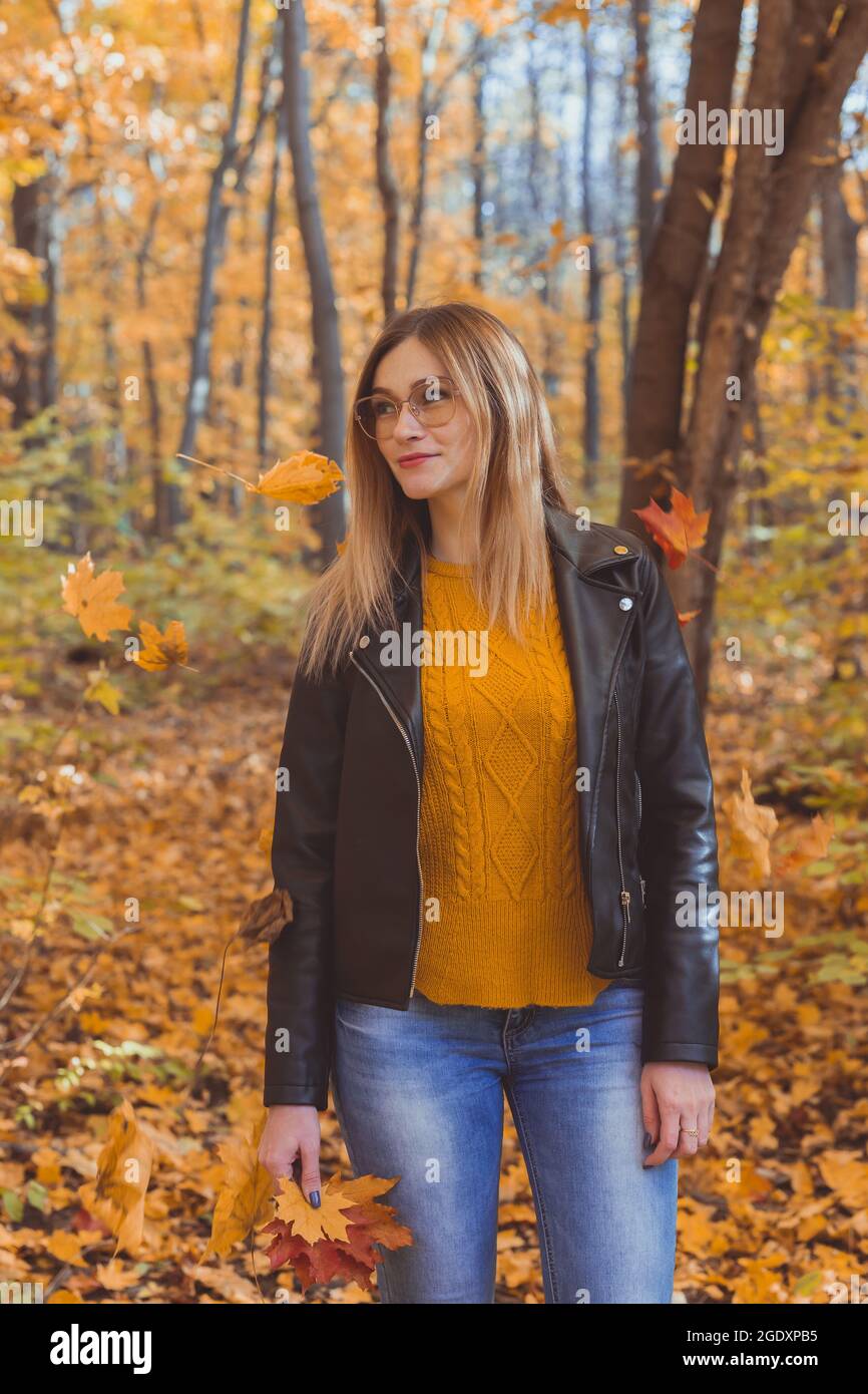 Cute smiley woman holding autumn leaves in fall park. Seasonal ...