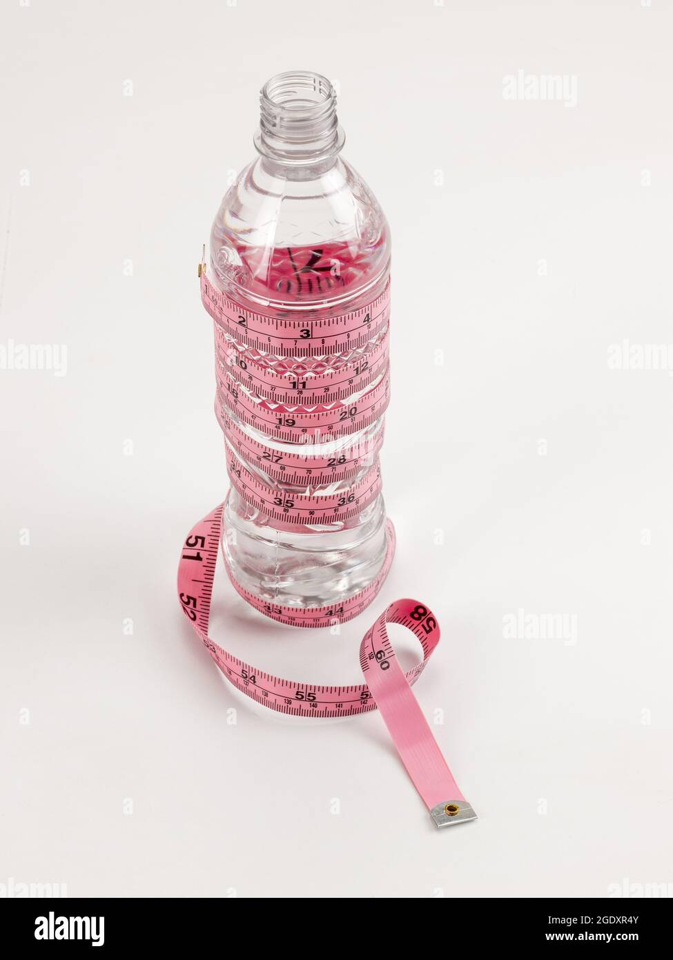 A pink tape measure wrapped around a plastic bottle isolated on a white ...