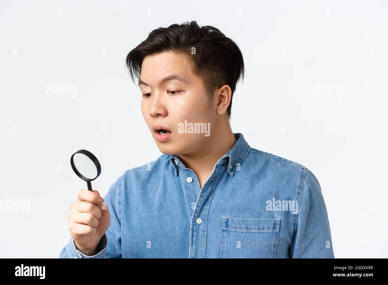 Close-up of young asian guy looking curious and focused, searching for ...