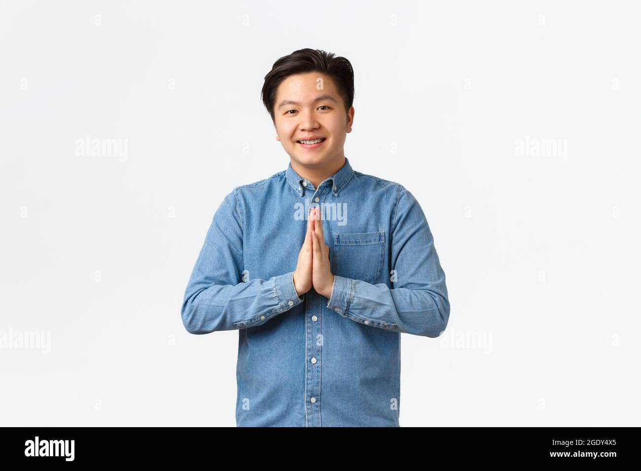 Smiling handsome young asian man looking thankful and pleased, holding ...