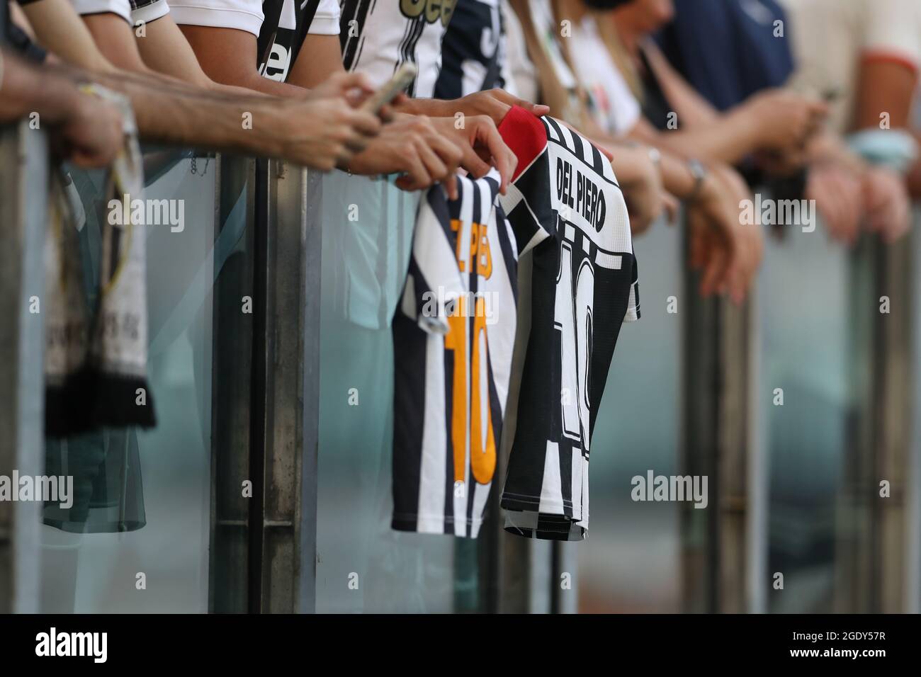 Turin, Italy, 14th August 2021. Juventus fans hold jerseys bearing the ...