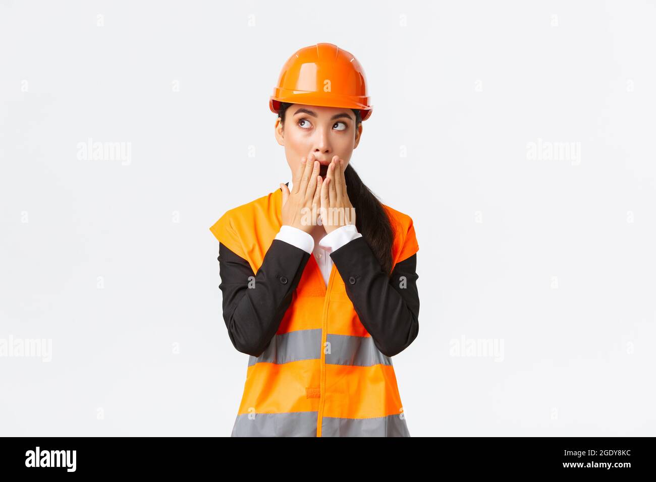 Shocked and concerned asian female engineer, architect in safety helmet ...