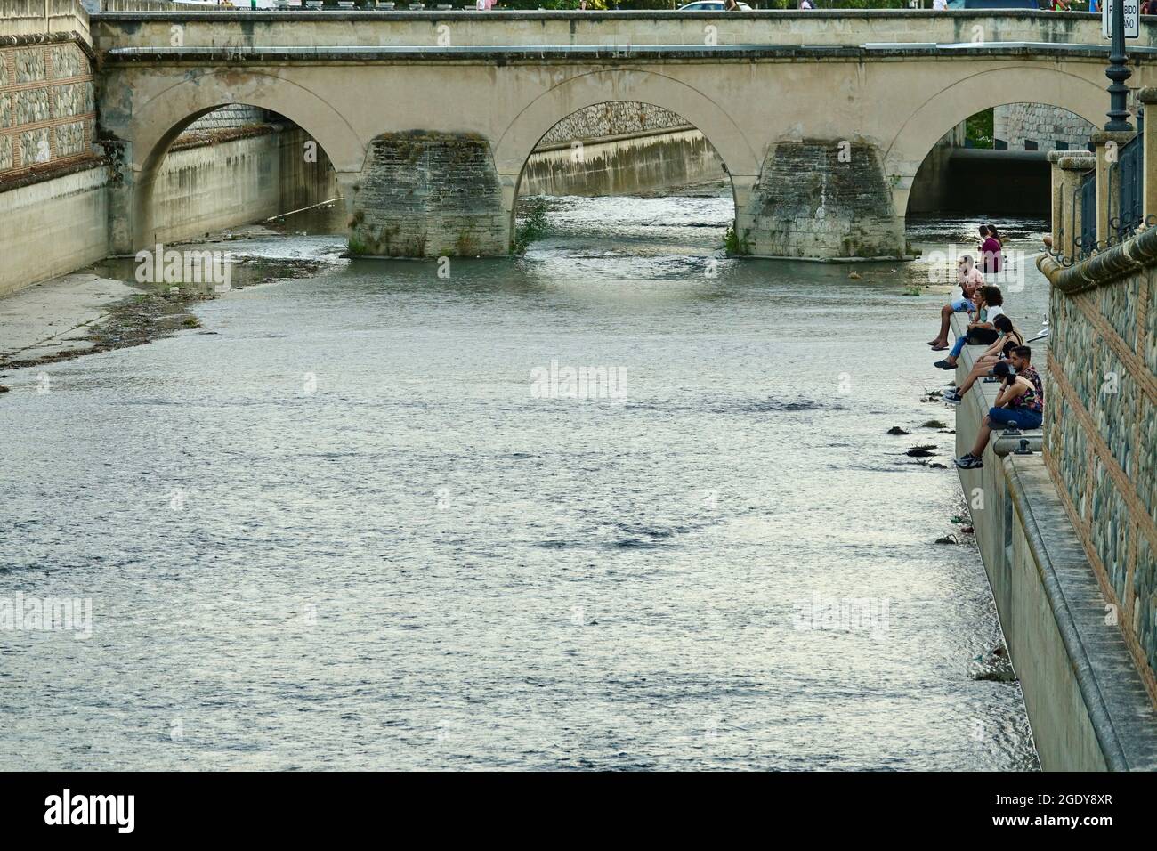 Granada, Spain; July-14, 2021: People sitting on the banks of the Genil ...