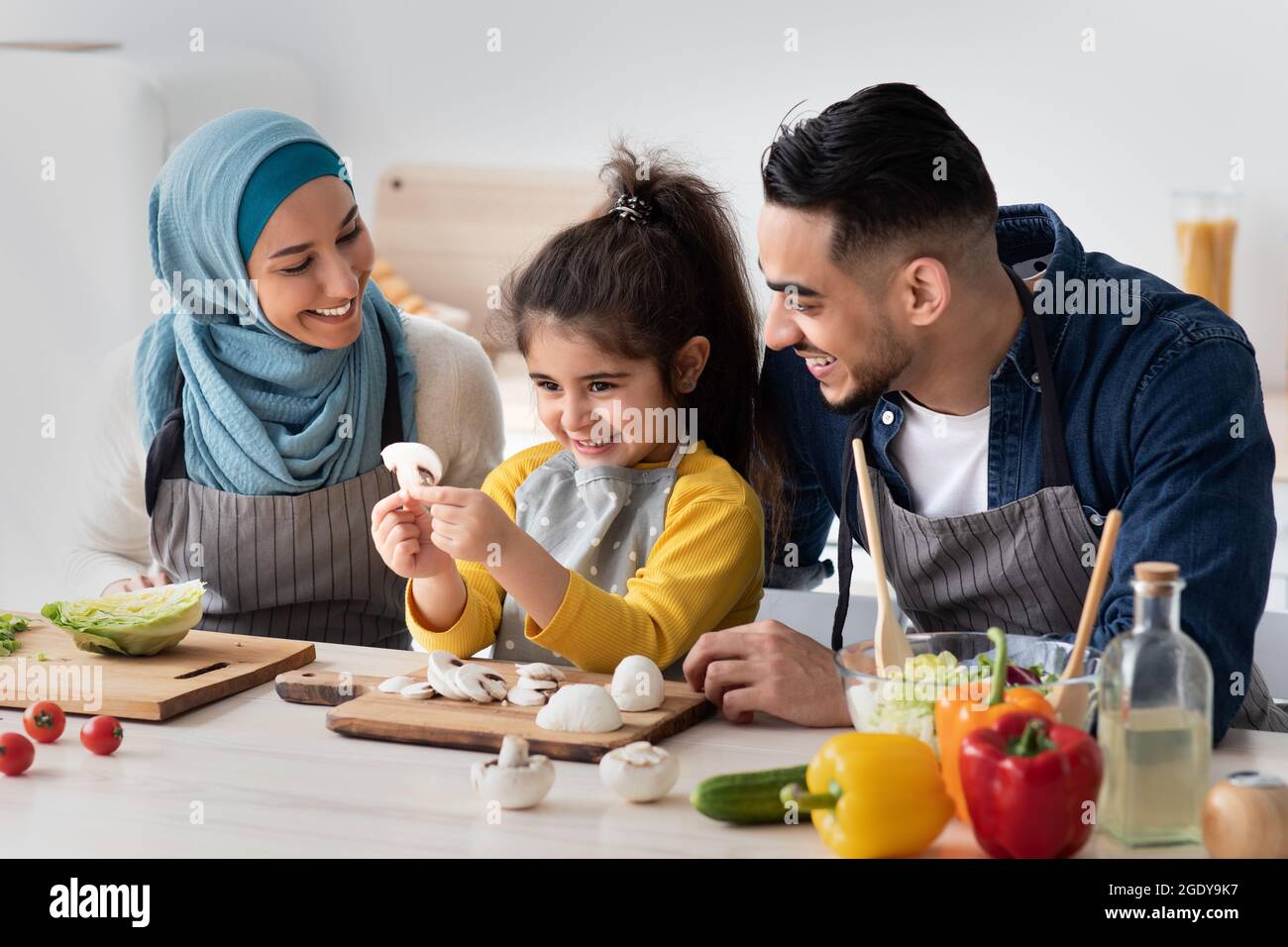 Portrait Of Cute Little Arab Girl Cooking With Parents In Kitchen Stock ...