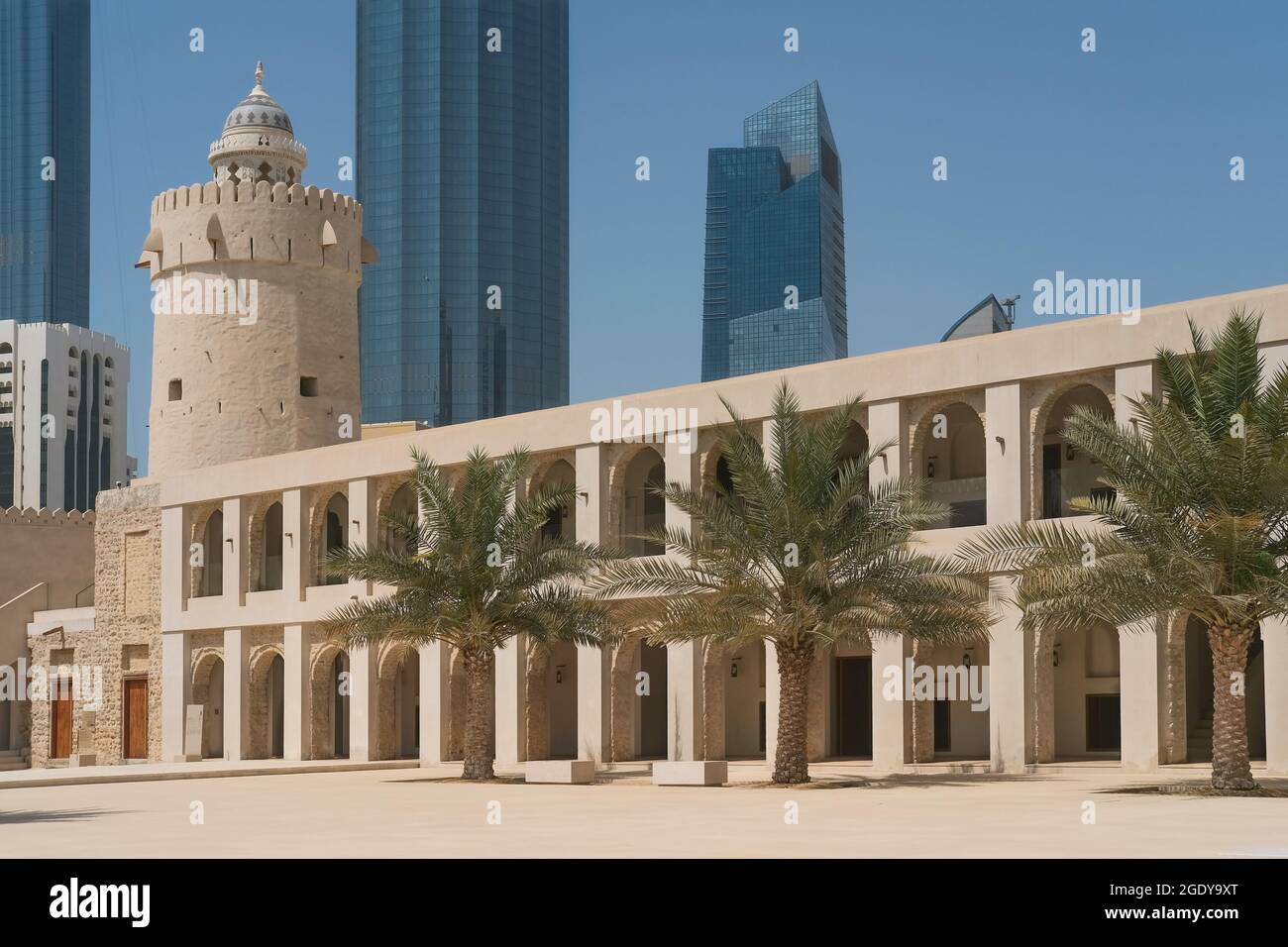 Courtyard with arched arcade,palm trees and Watchtower of Qasr al-Hosn ...