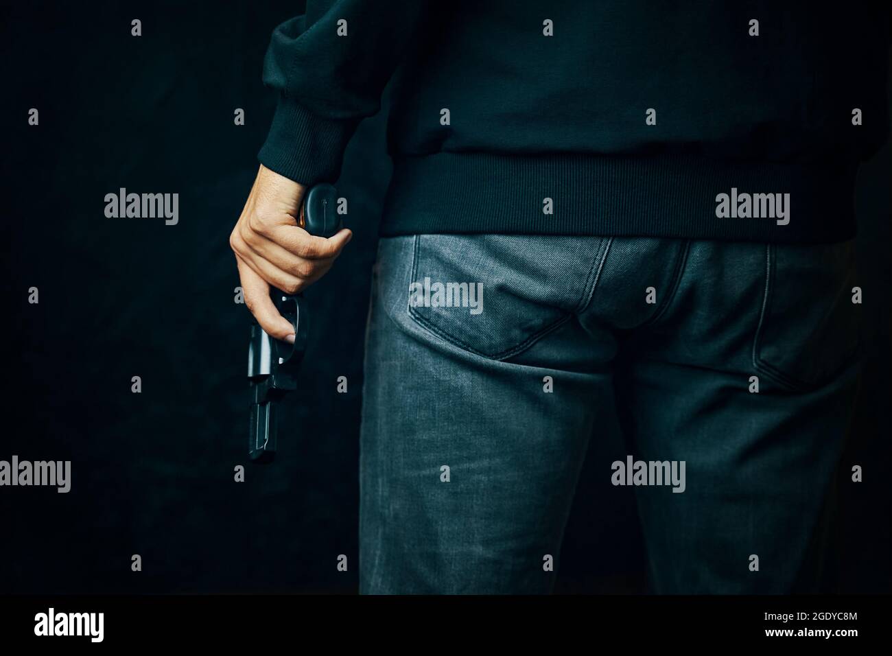 Man in sweater and jeans is holding gun. Criminal with revolver on ...