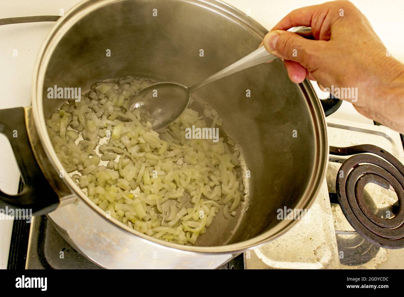 Fry the chopped onion in oil in a saucepan. A woman's hand mixes the ...