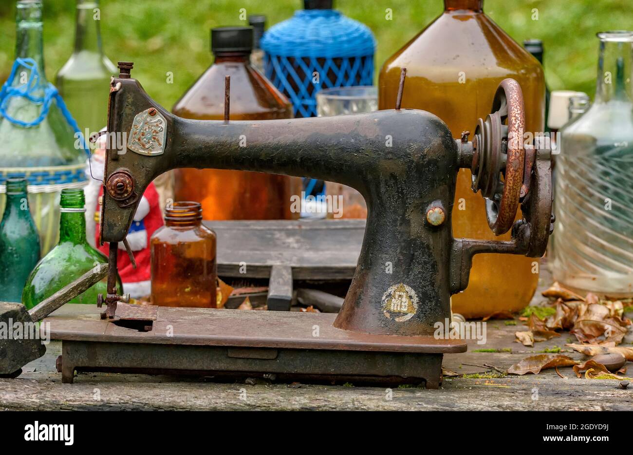 An old discarded hand sewing machine and glass bottles of assorted ...