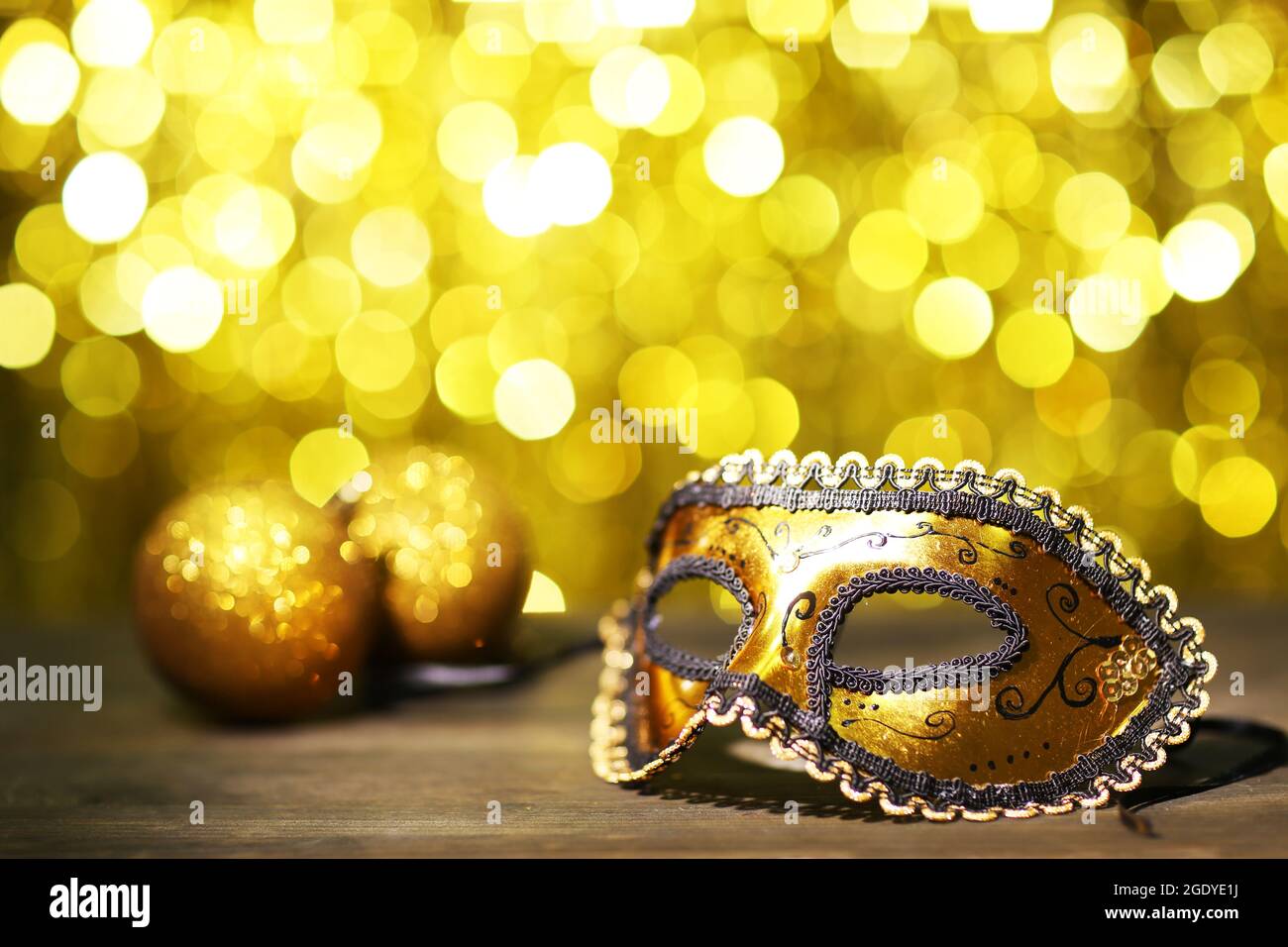 Beautiful carnival mask on table on golden background Stock Photo - Alamy