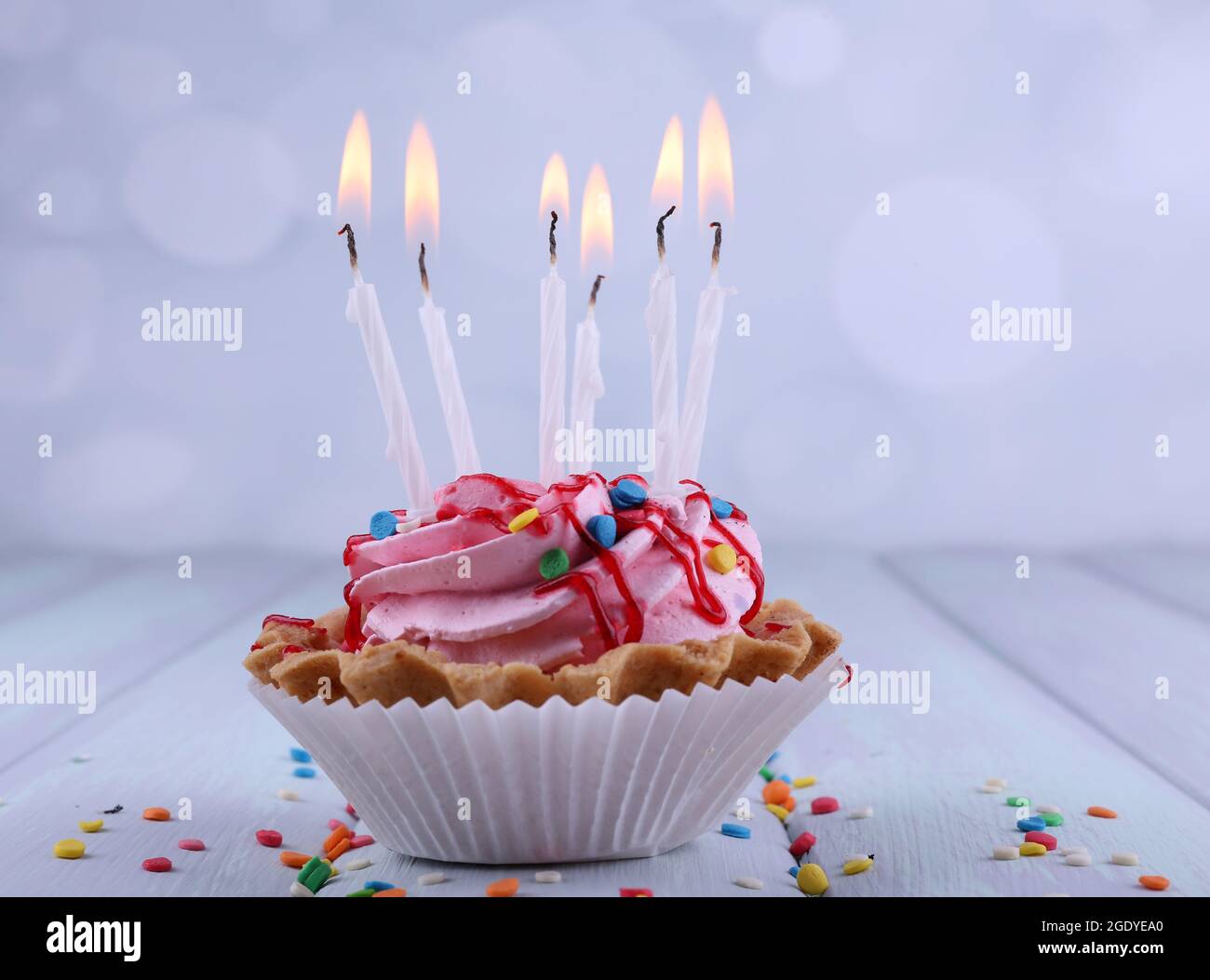 Birthday cup cake with candles and sparkles on color wooden table and ...