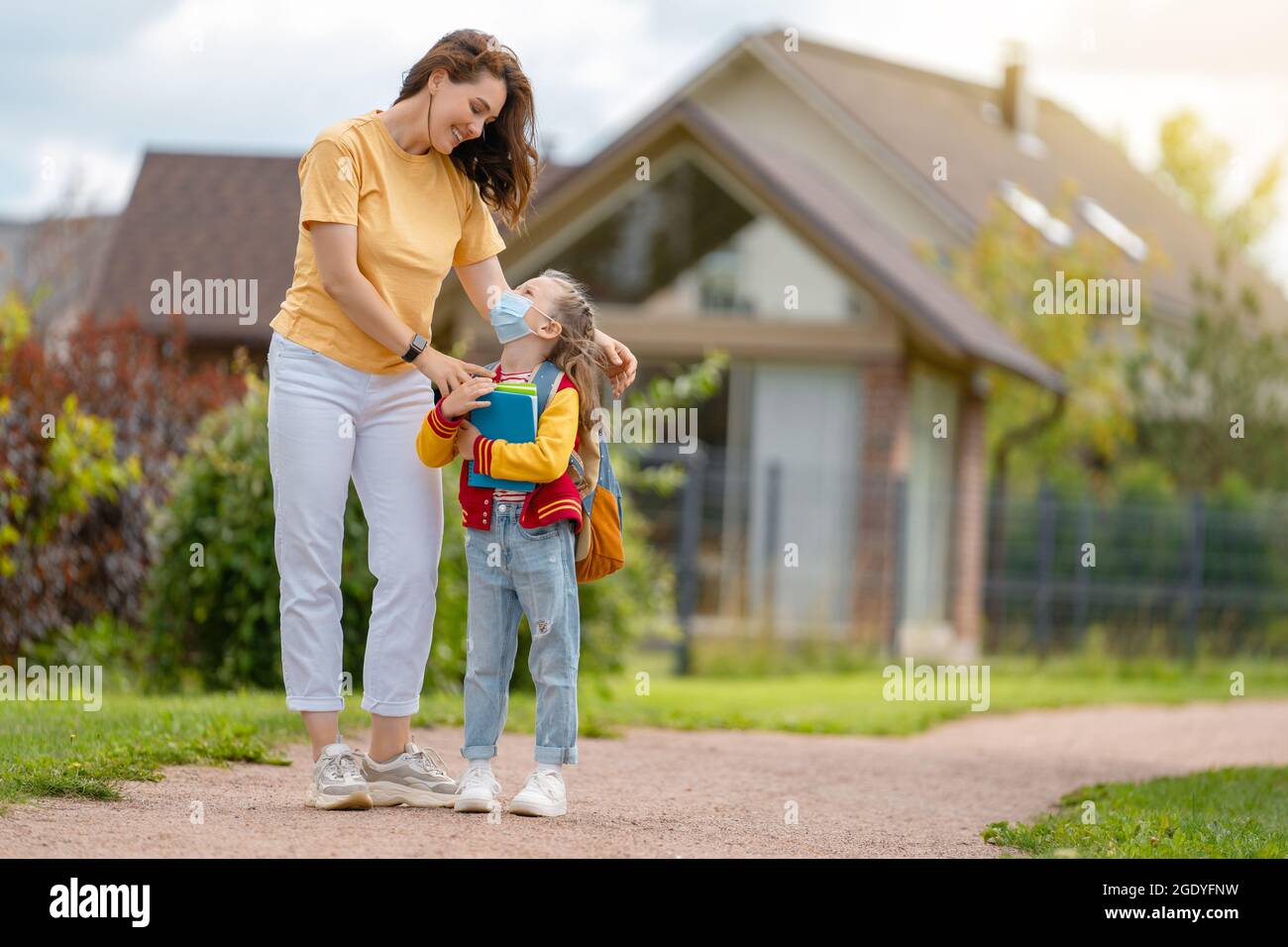 Parent and pupil of primary school going hand in hand. Woman and girl ...