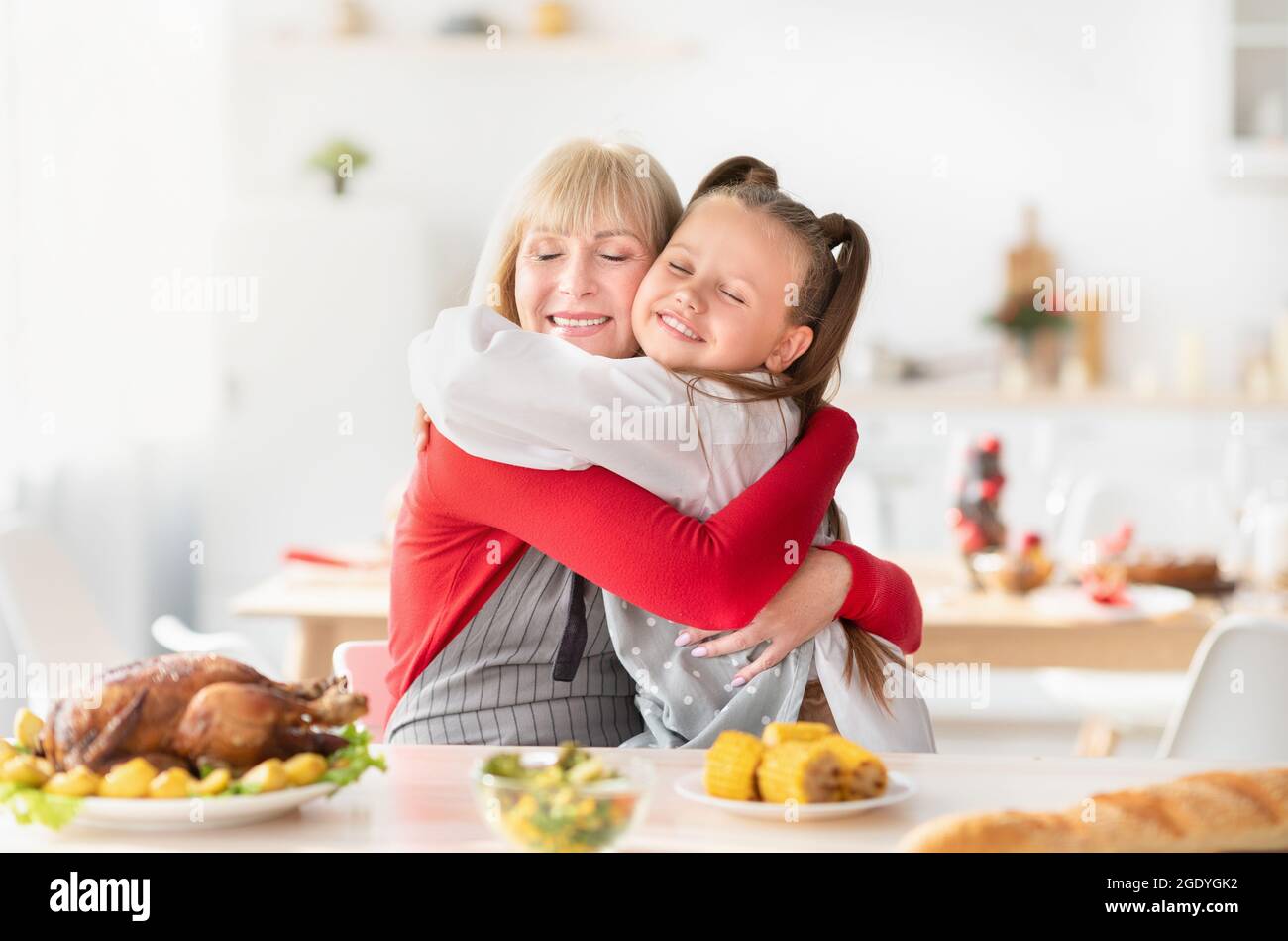 Happy granny hugging granddaughter while cooking traditional holiday ...