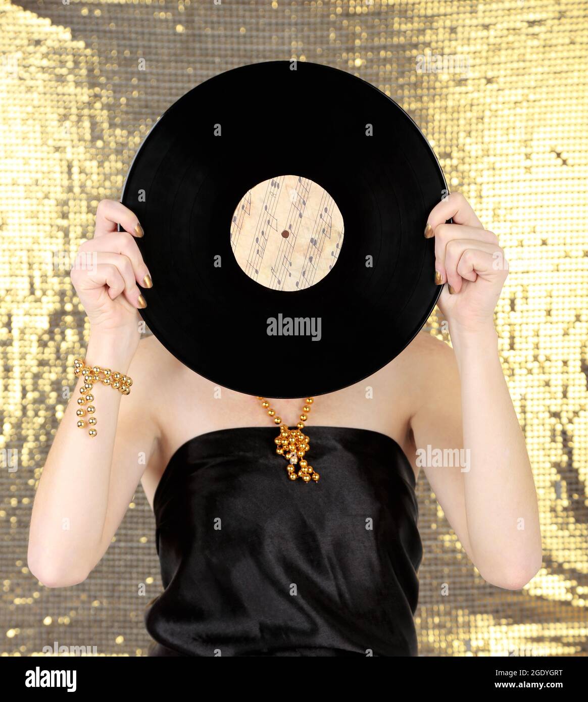 Young woman holding retro record in front of face, on shiny background ...