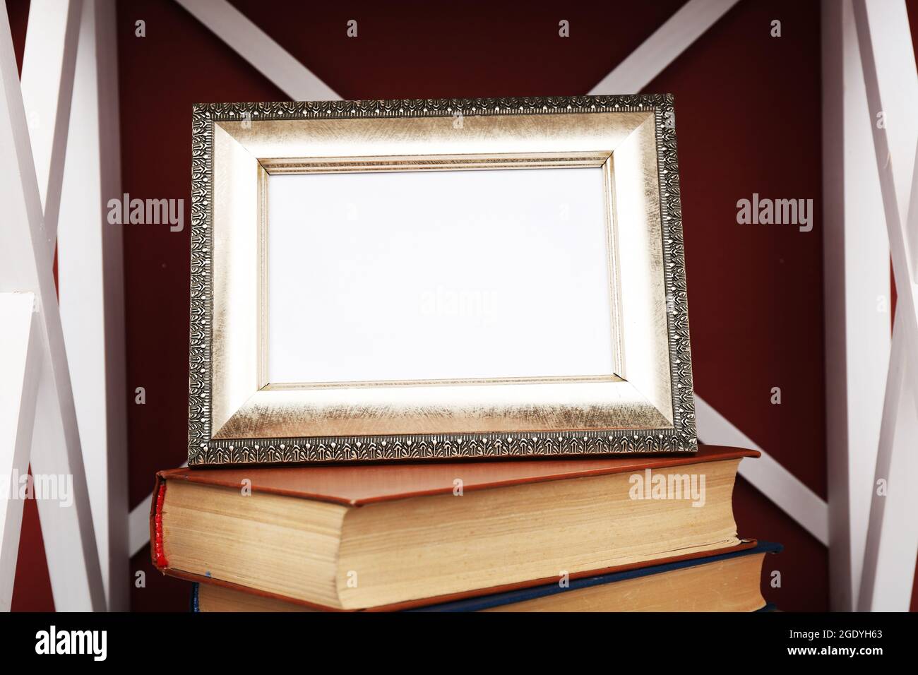 Photo frame with books on shelf, on color wall background Stock Photo ...